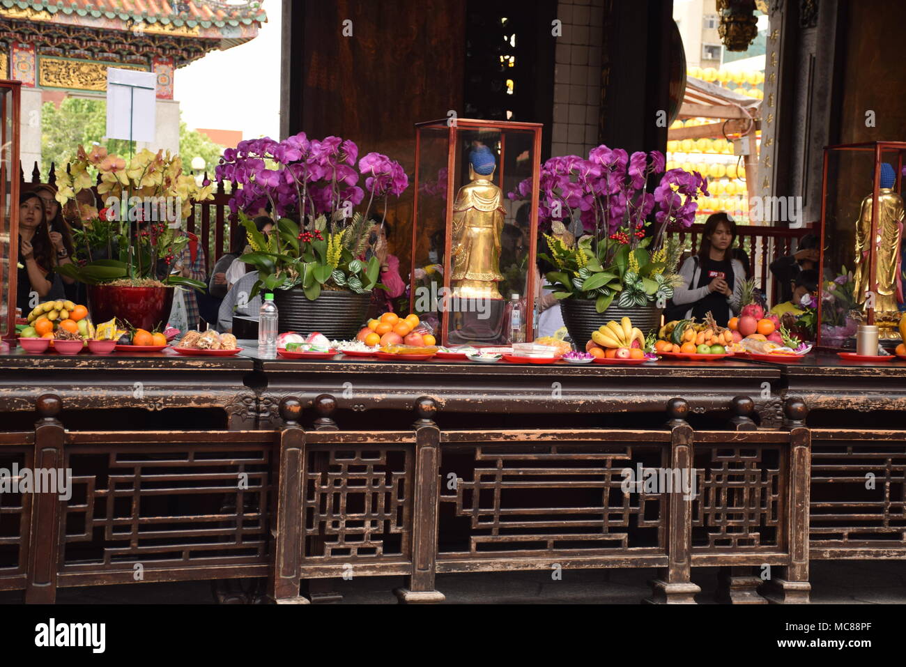 Food, fruits, flowers and other offerings on a table inside Longshan ...