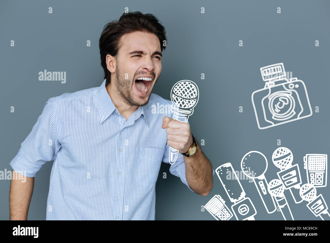 Enthusiastic singer holding a microphone and singing loudly Stock Photo ...