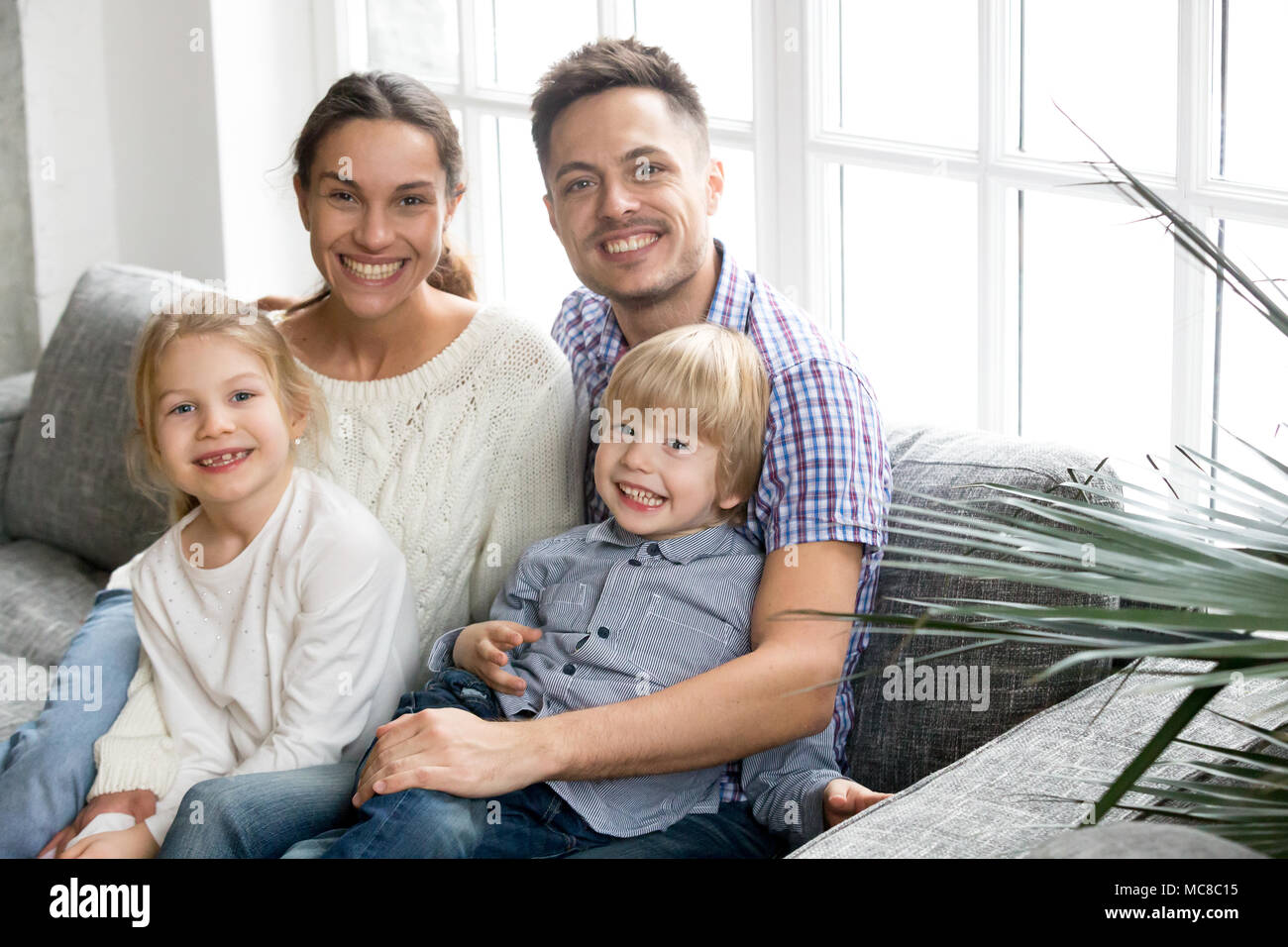 Portrait of happy multi-ethnic family embracing adopted kids siblings ...