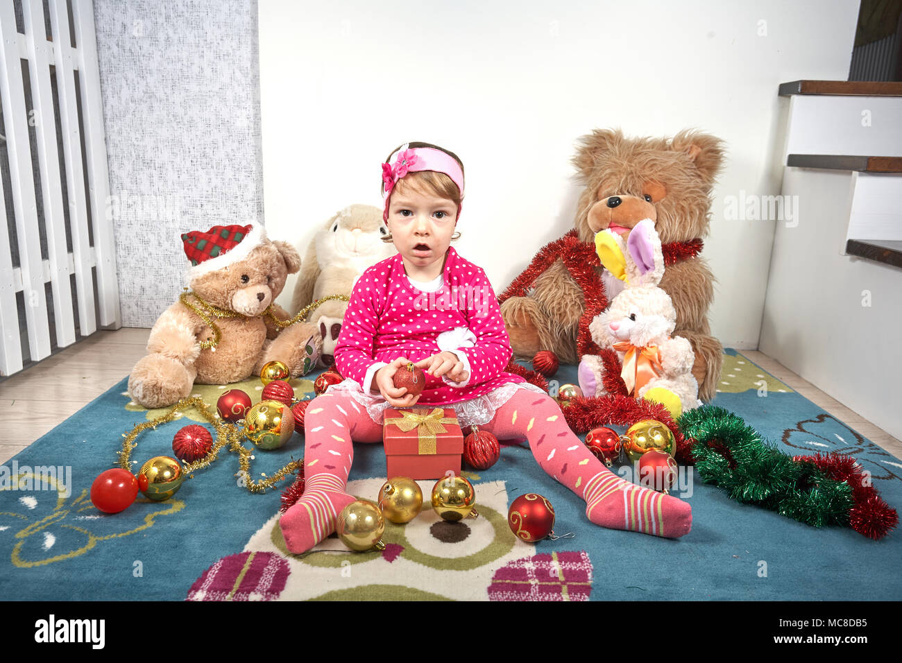 Adorable happy little girl kidin a red dress and a head band made of ...