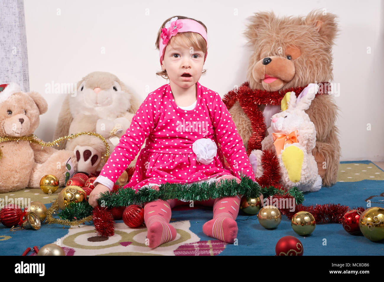 Adorable happy little girl kidin a red dress and a head band made of ...