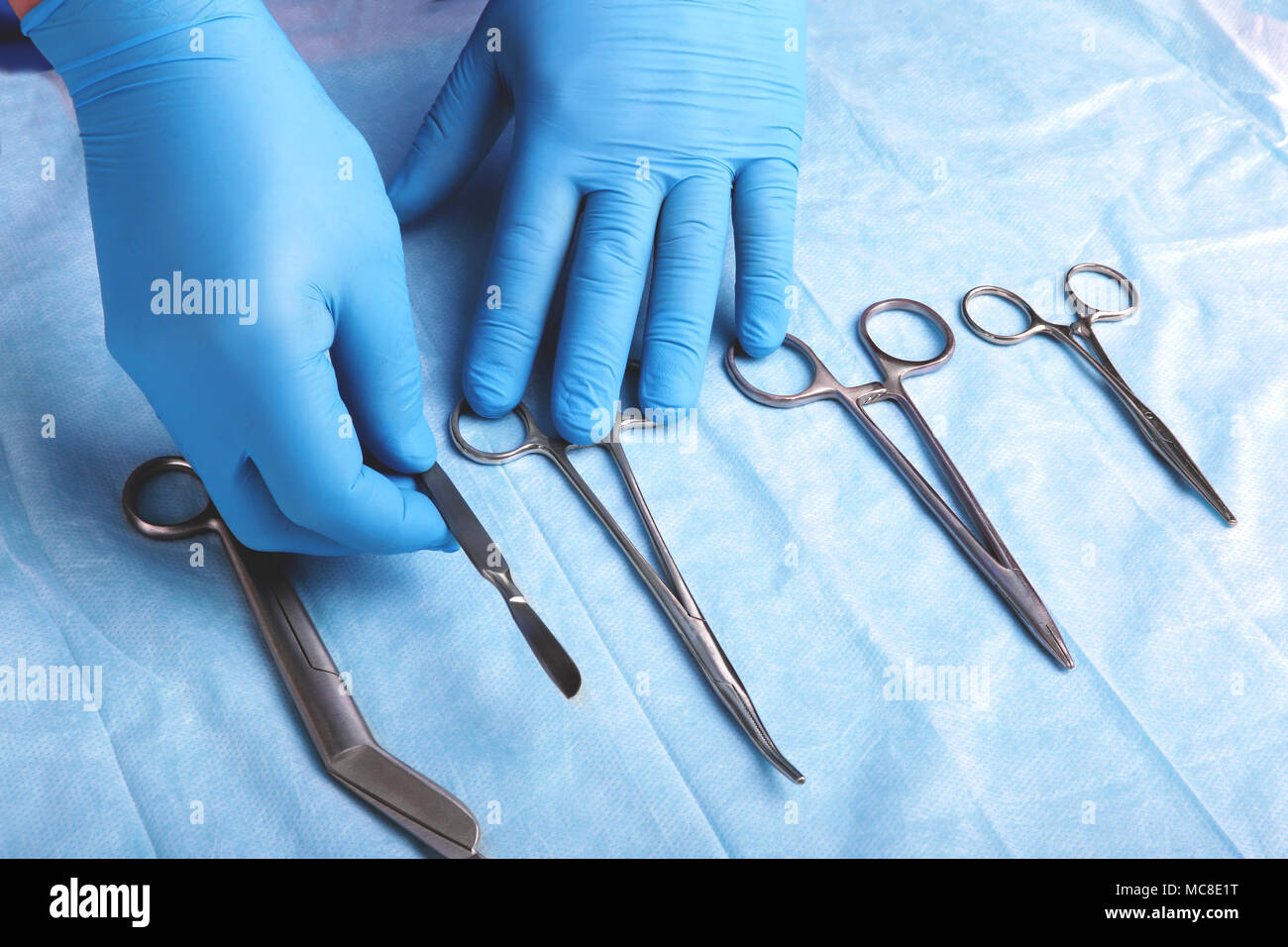 Detail shot of sterilized surgery instruments with a hand grabbing a ...