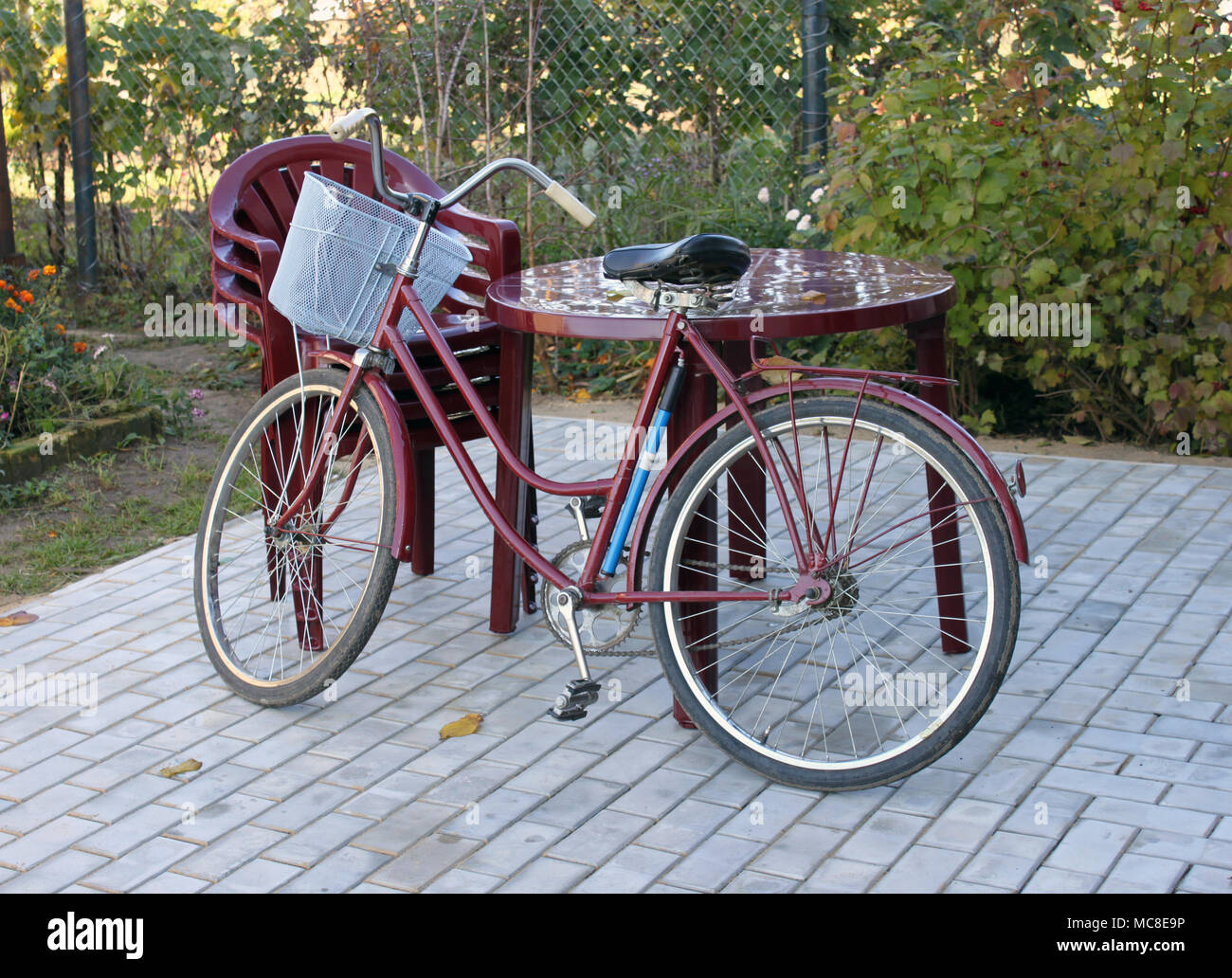 Plastic furniture and old red bicycle on a patio Stock Photo - Alamy