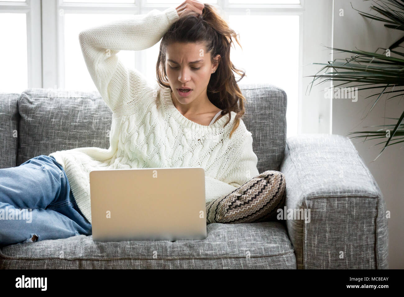 Shocked young woman looking at laptop computer screen at home ...