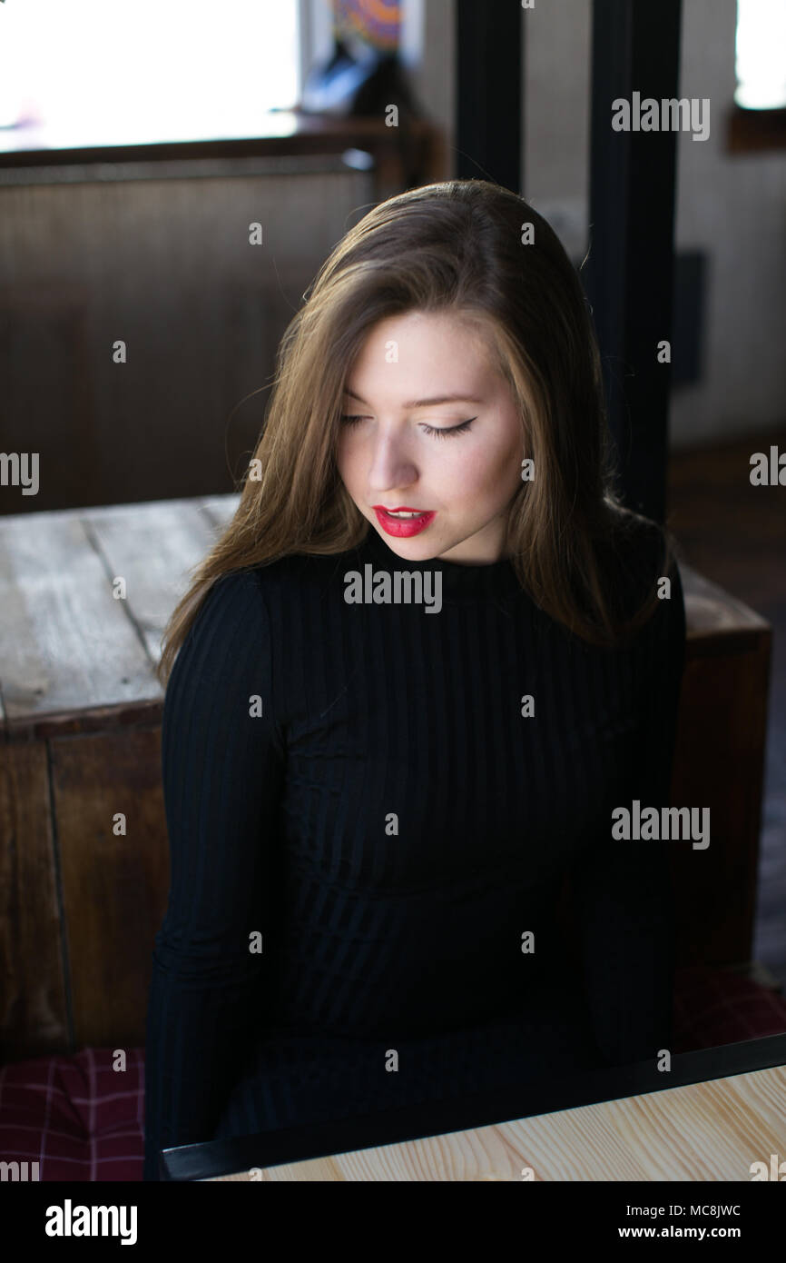 Girl sitting near table in cafe Stock Photo - Alamy