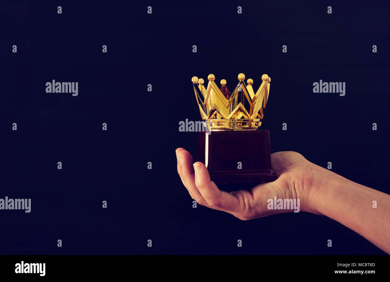 Man's hand holding crown award trophy for show victory or winning first ...