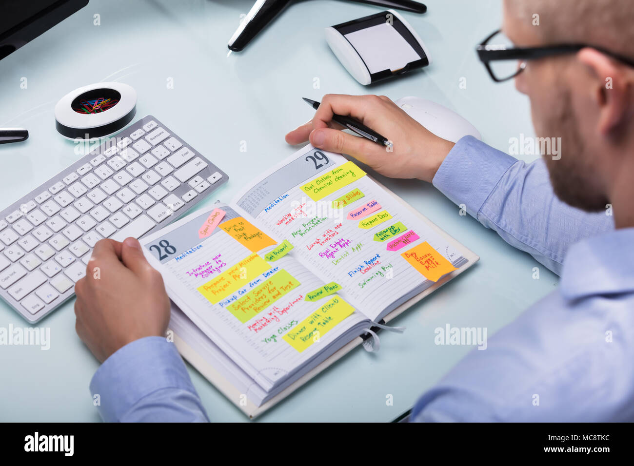 Businessman's Hand Writing Schedule In Diary With Pen At Workplace ...