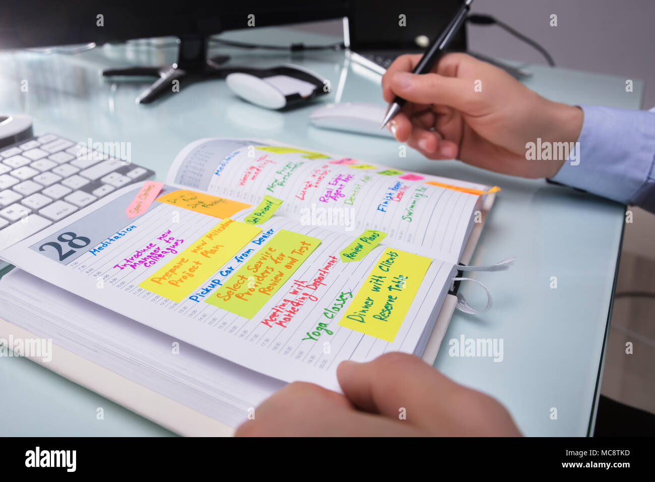 Businessman's Hand Writing Schedule In Diary With Pen At Workplace ...