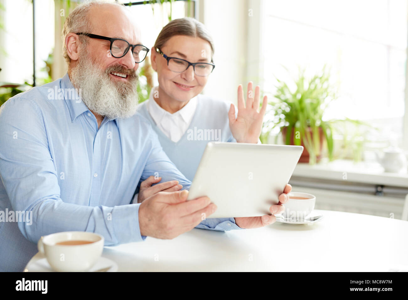 Happy seniors with tablet chatting with their relatives, children or ...