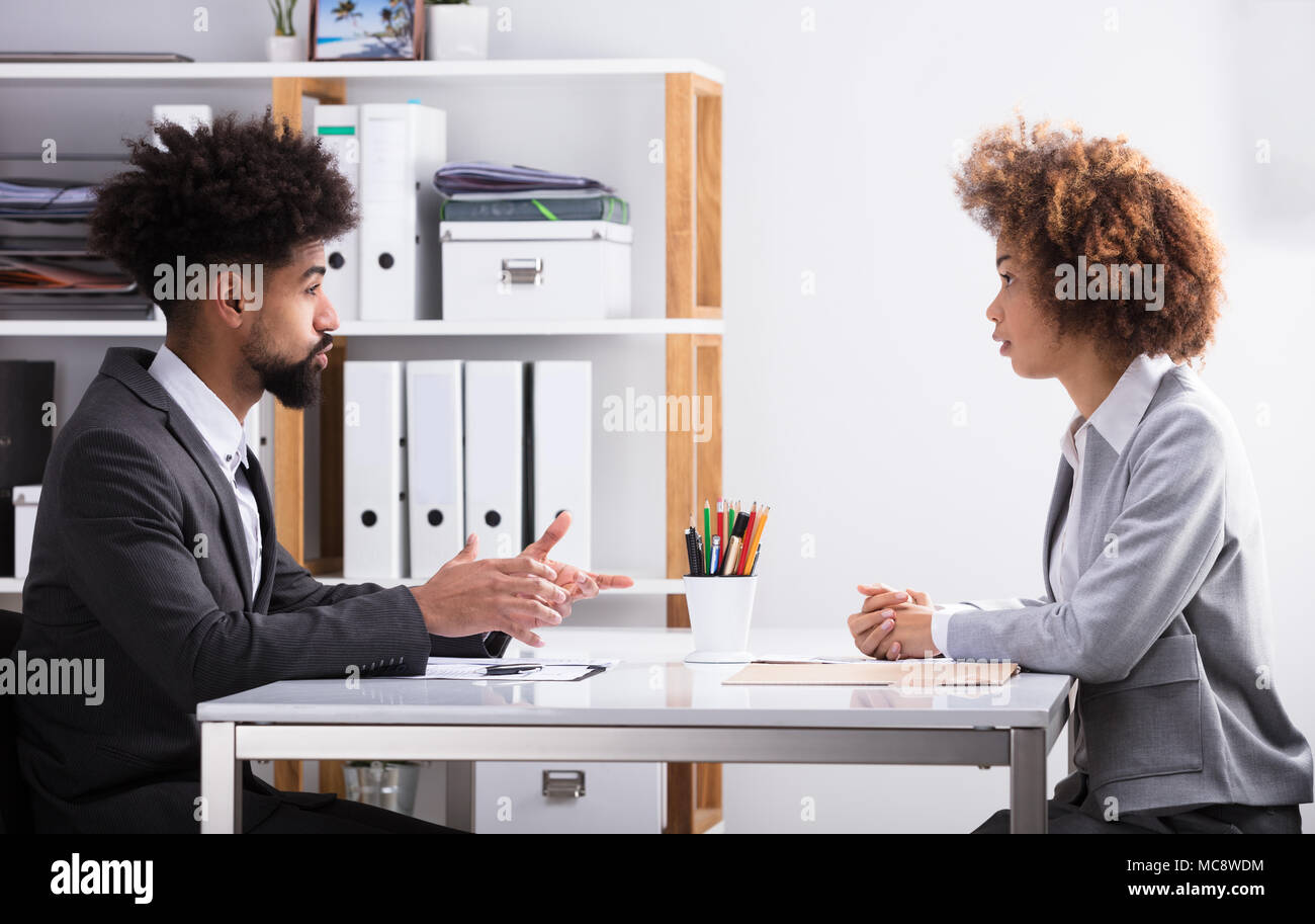 Side View Of Two Young Businesspeople Having Conversation In Office ...