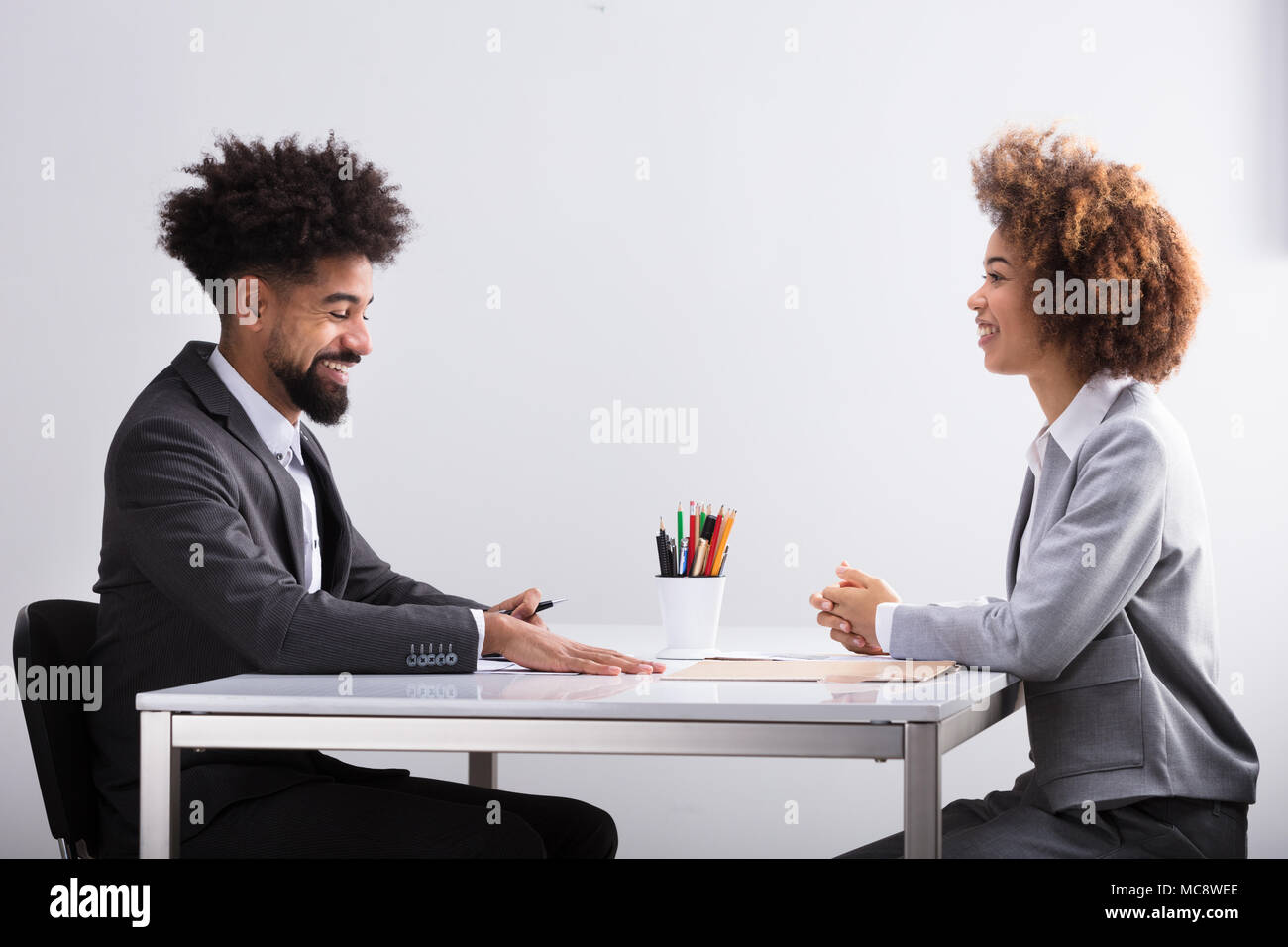 Side View Of Two Young Businesspeople Having Conversation In Office ...
