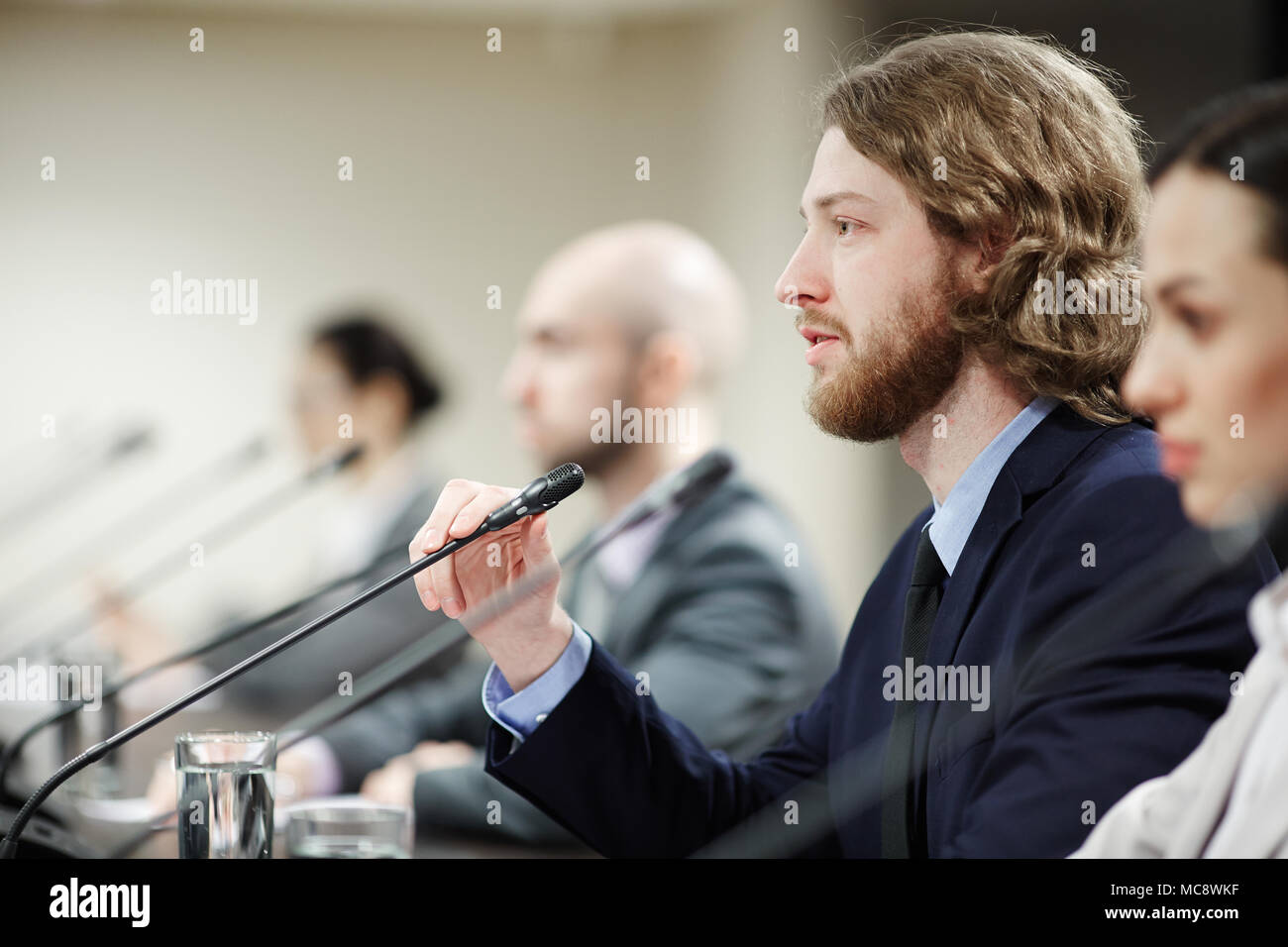 Young serious speaker making report for audience at political ...