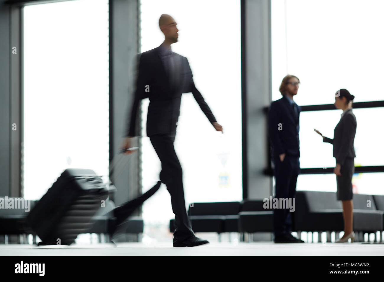 Blurry human figure moving along airport lounge with suitcase and ...