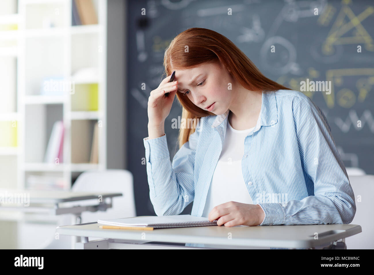 Serious student concentrating on reading her lecture notes before ...