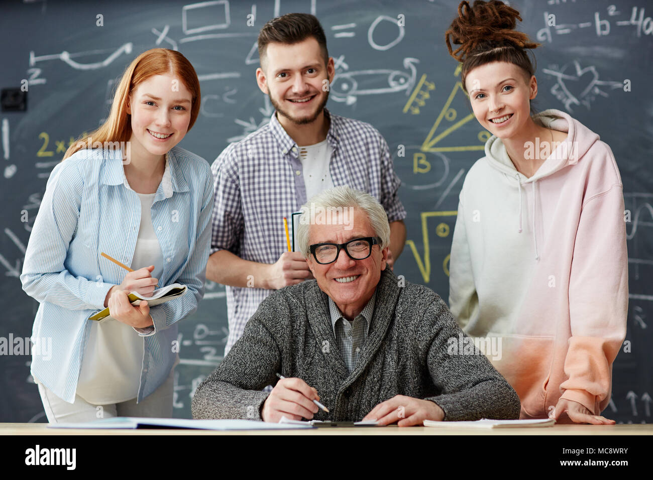 Happy professor and his successful students looking at camera on ...