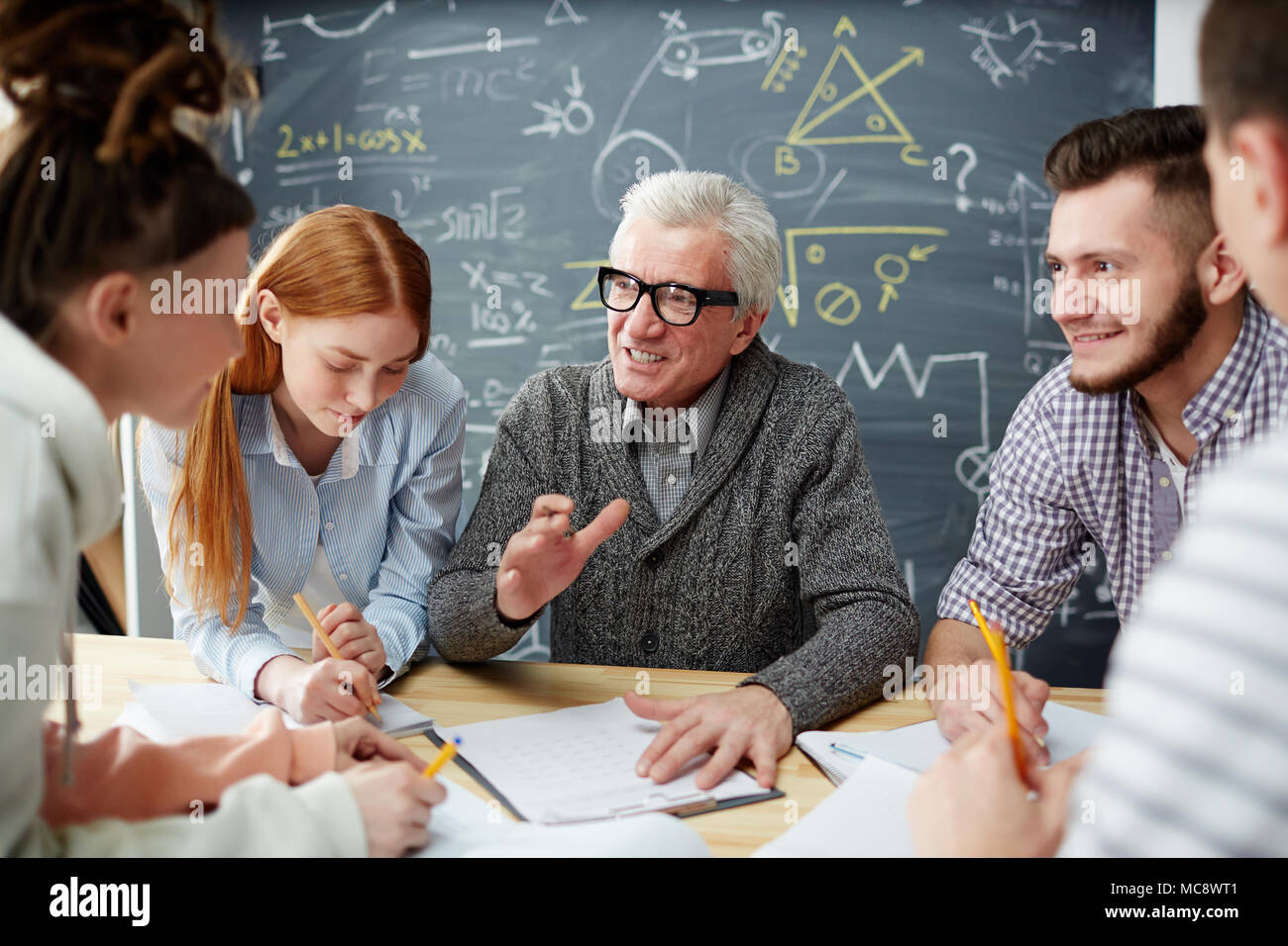 Confident teacher explaining details of his lecture points to group of ...