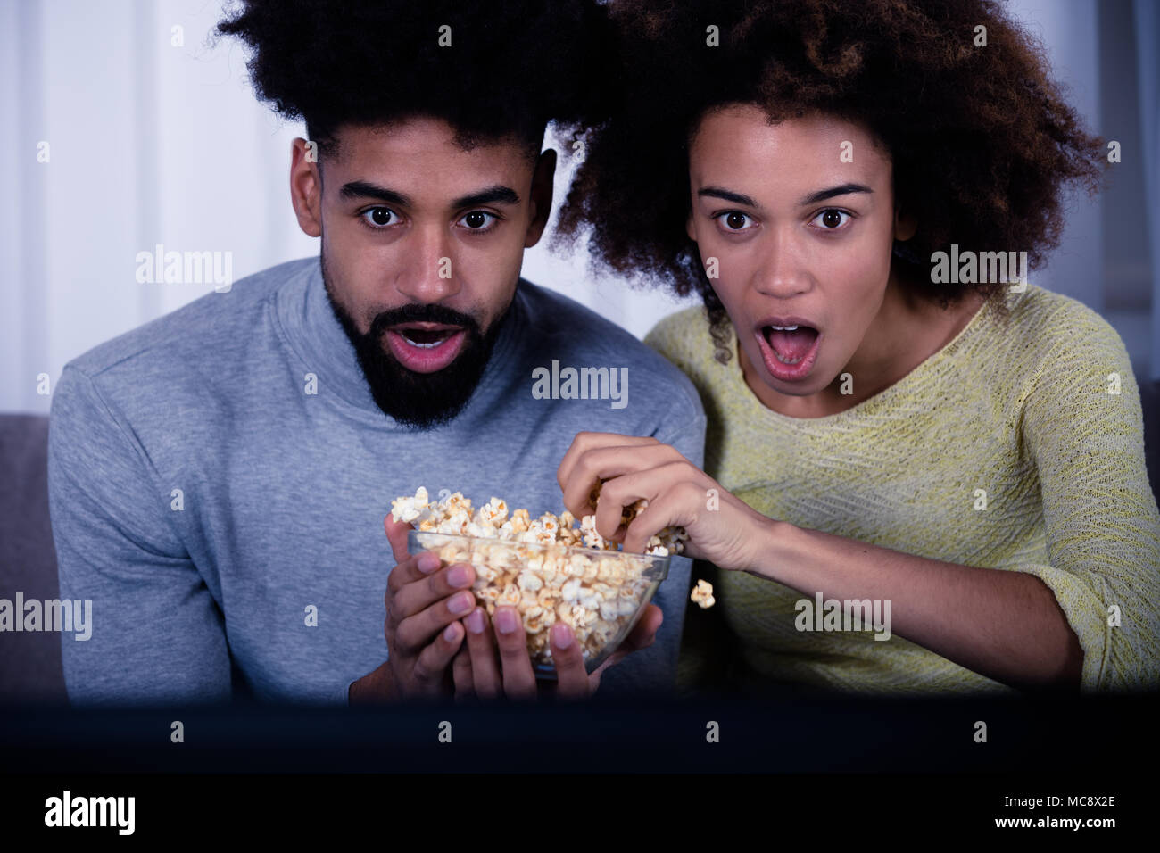 Shocked Couple Eating Popcorn While Watching Movie Stock Photo - Alamy