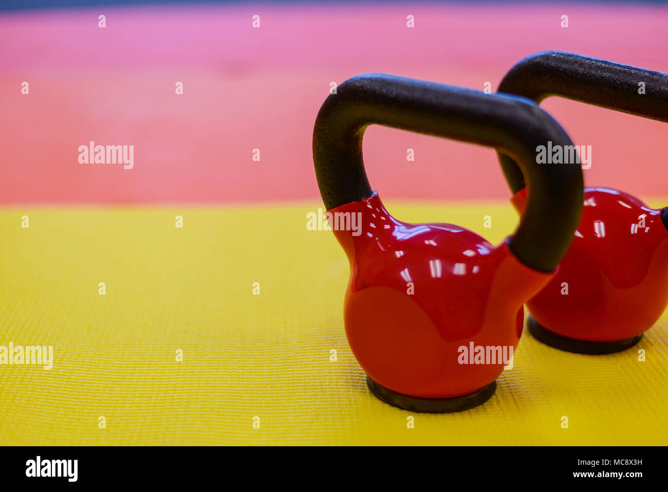 a set of two red kettle bells sitting on colorful exercise mats ...