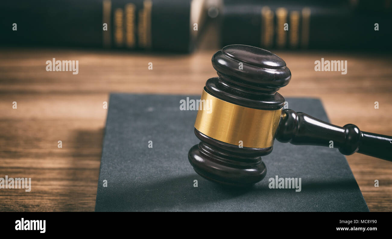 Law or auction gavel on a book, wooden office desk with blur books ...