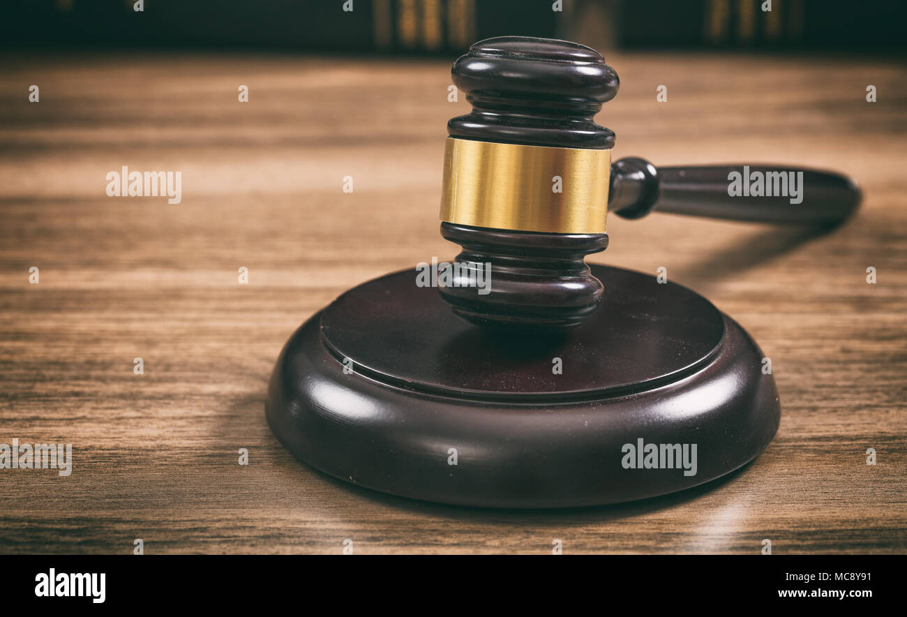 Law or auction gavel on a wooden office desk. Closeup front view with ...
