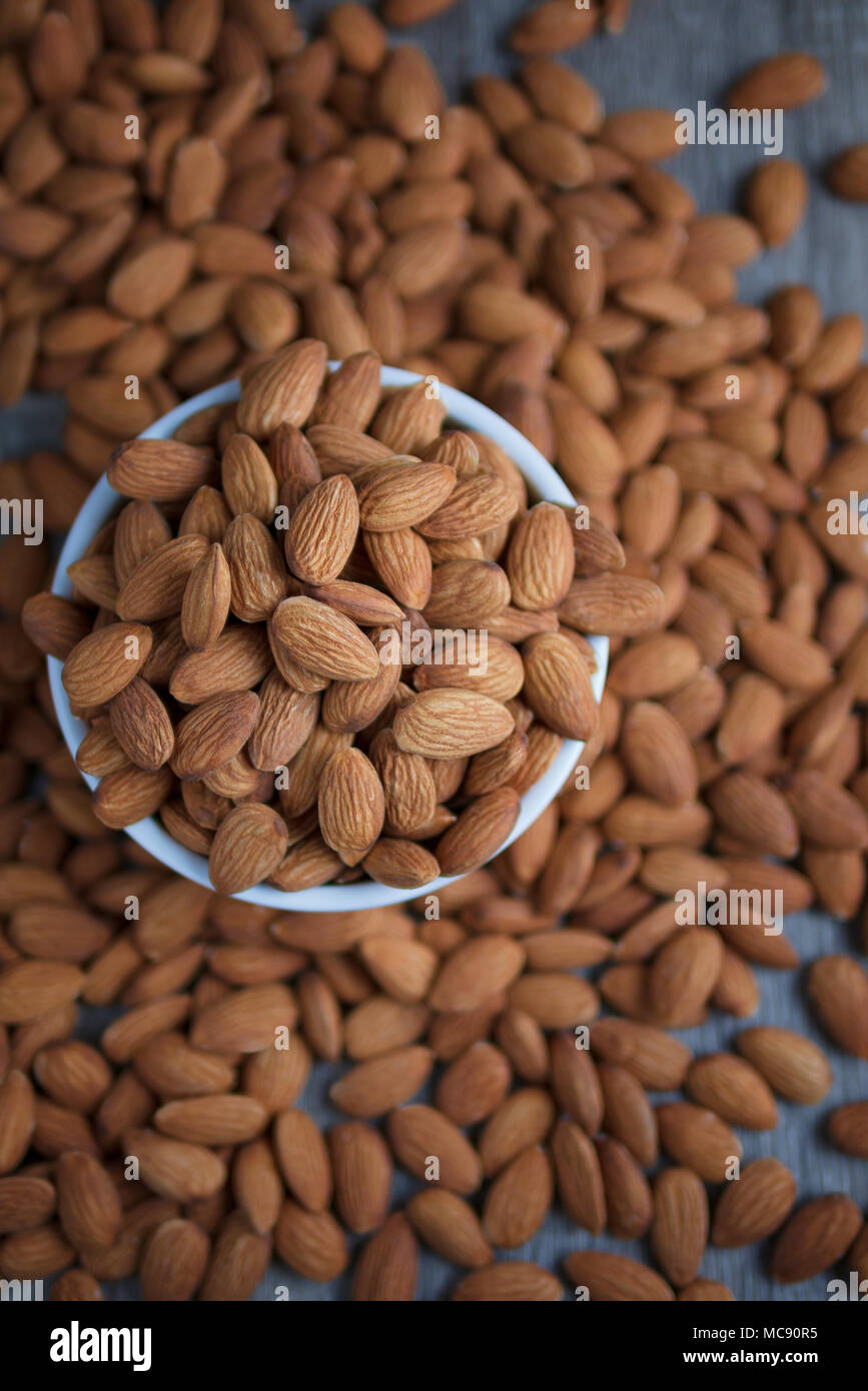 Pile of almonds nut in a while bowl against dark rustic wooden ...