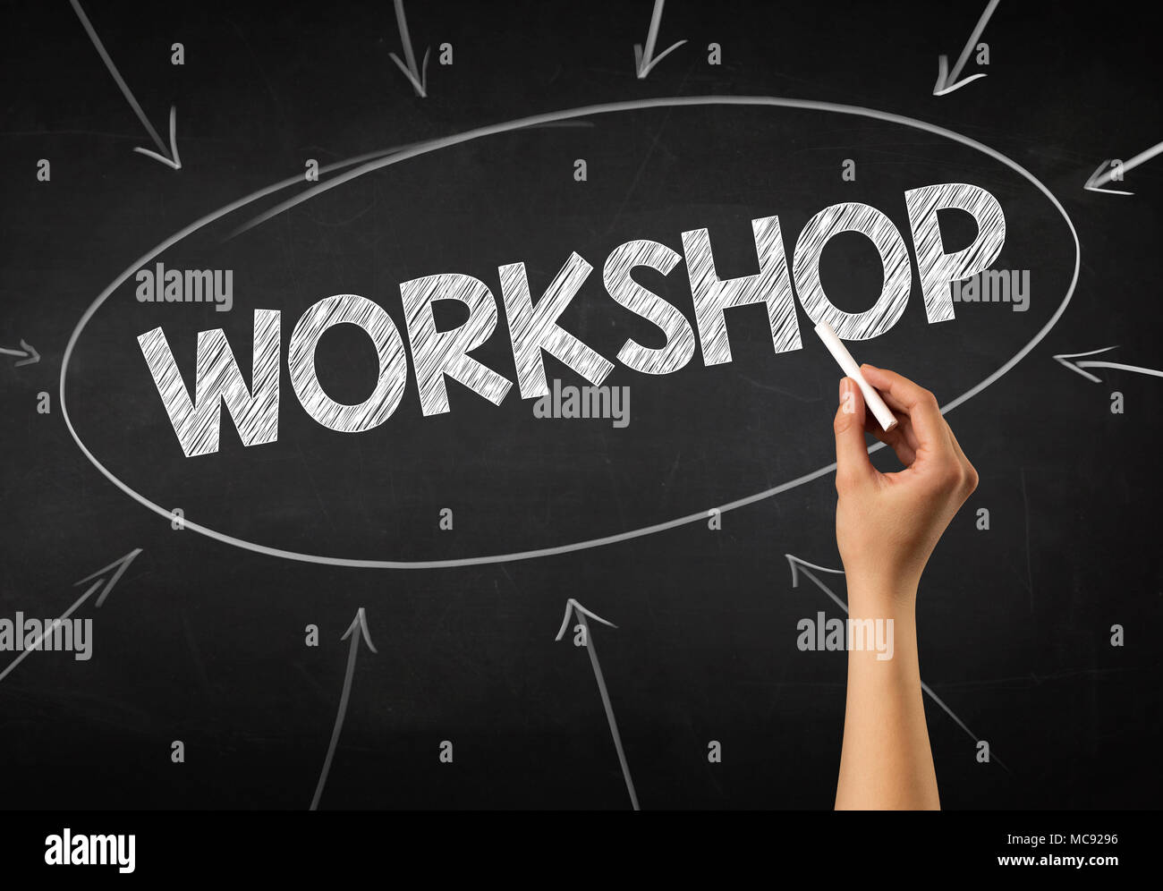 Female hand holding white chalk in front of a blackboard with workshop ...