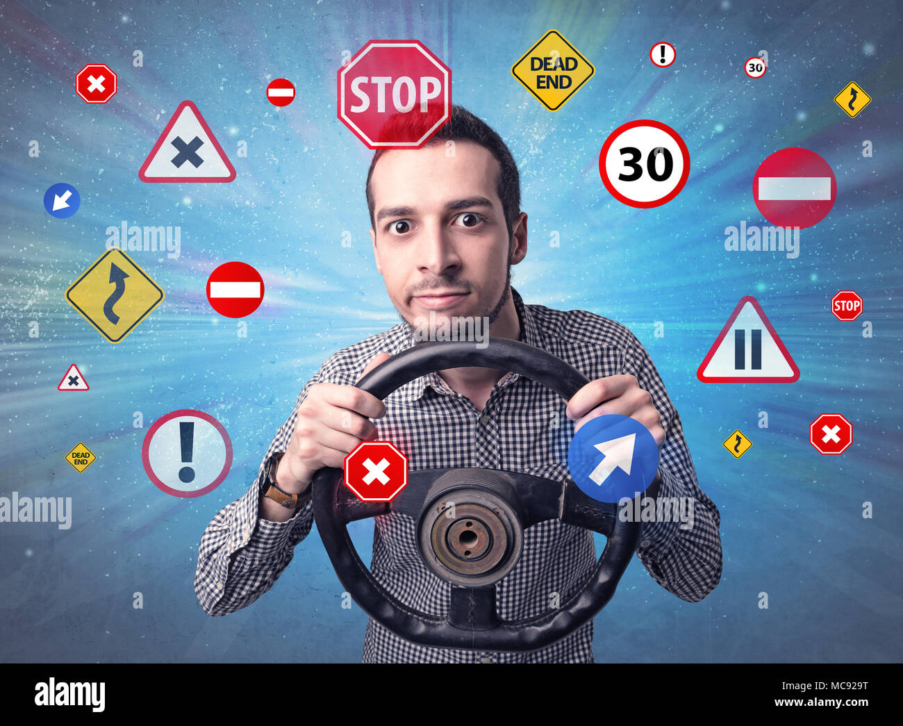Young man holding black steering wheel with road signs surrounding him ...