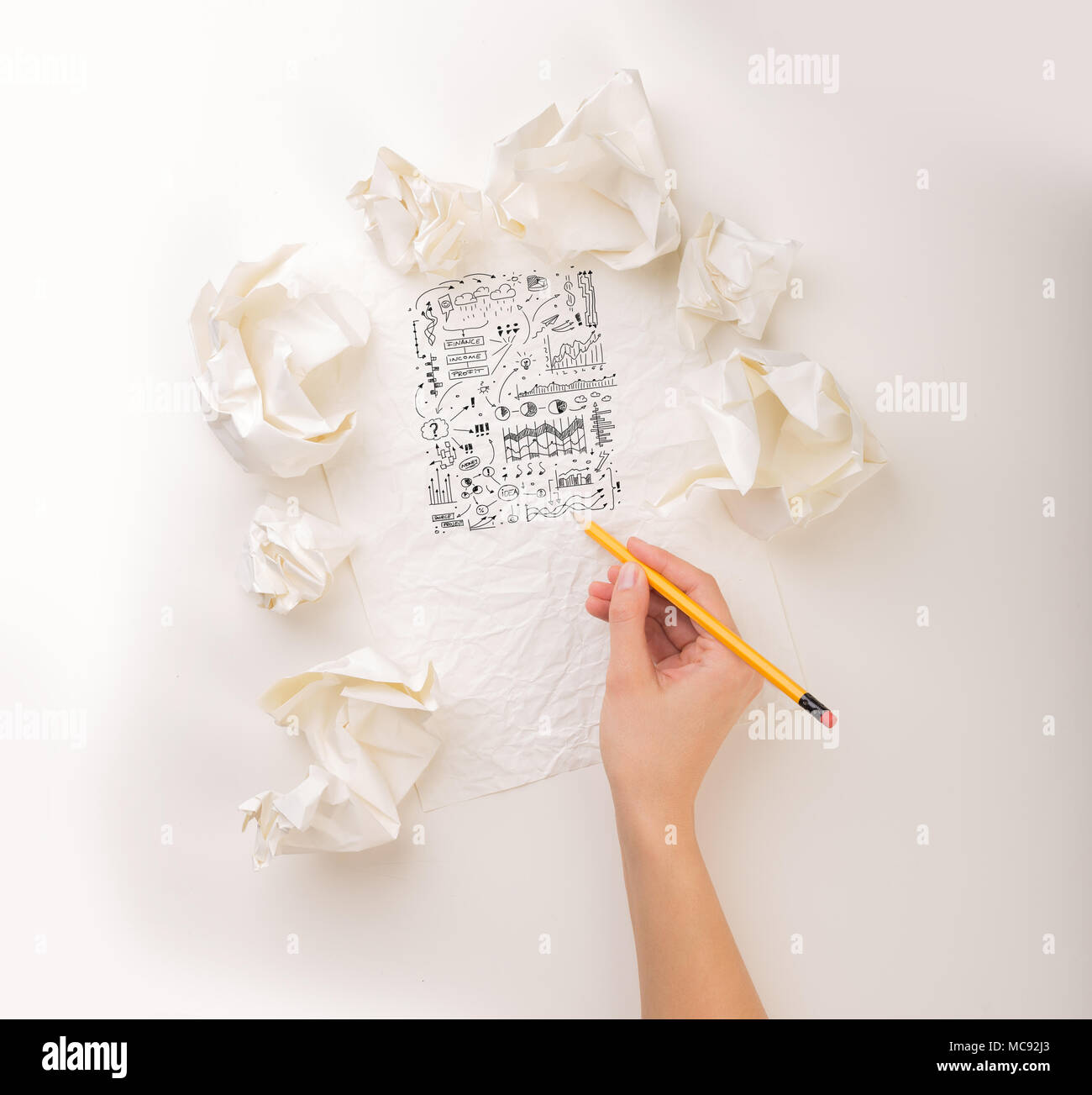 Female hand next to a few crumpled paper balls drawing charts and ...
