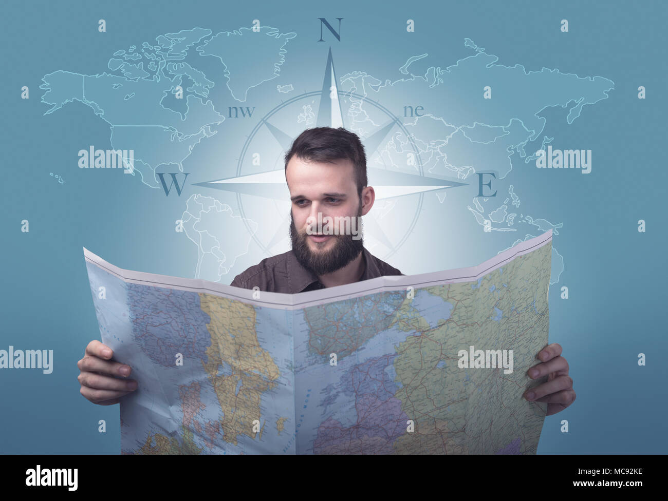 Handsome young man holding a map with a world map and a compass behind ...