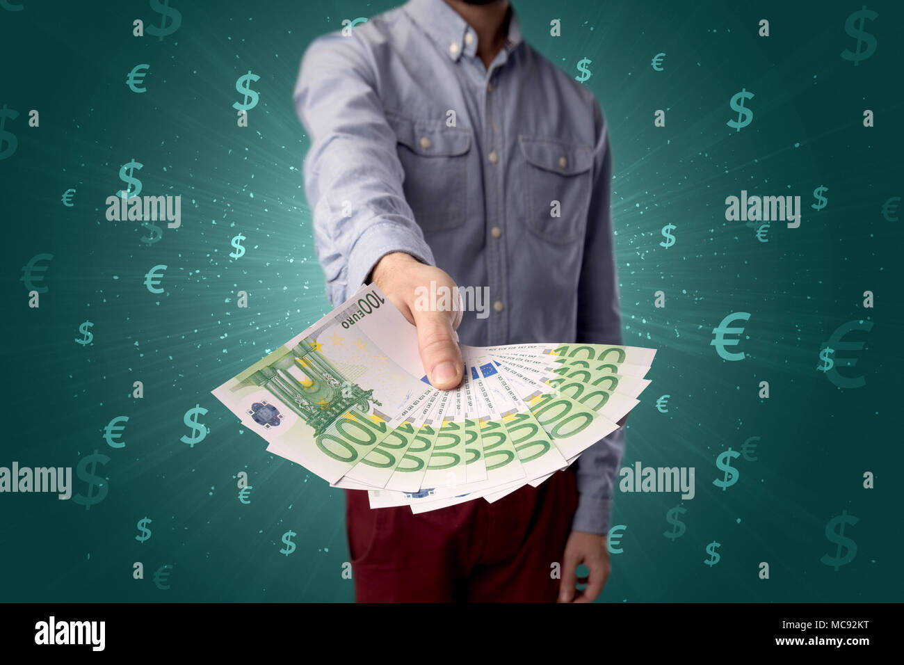Young businessman holding large amount of bills with green background ...