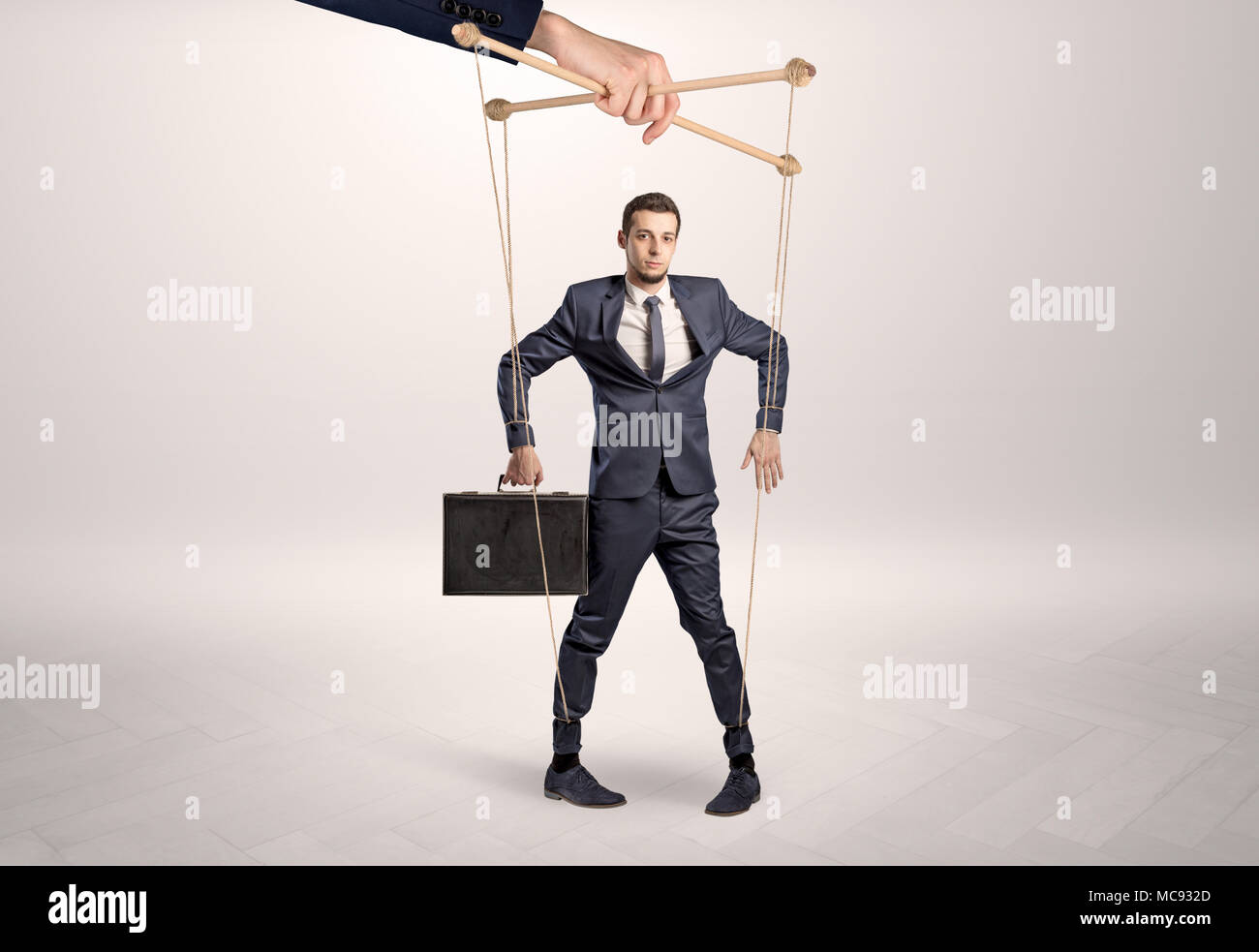 Puppet businessman in an empty room leaded by a huge hand Stock Photo ...