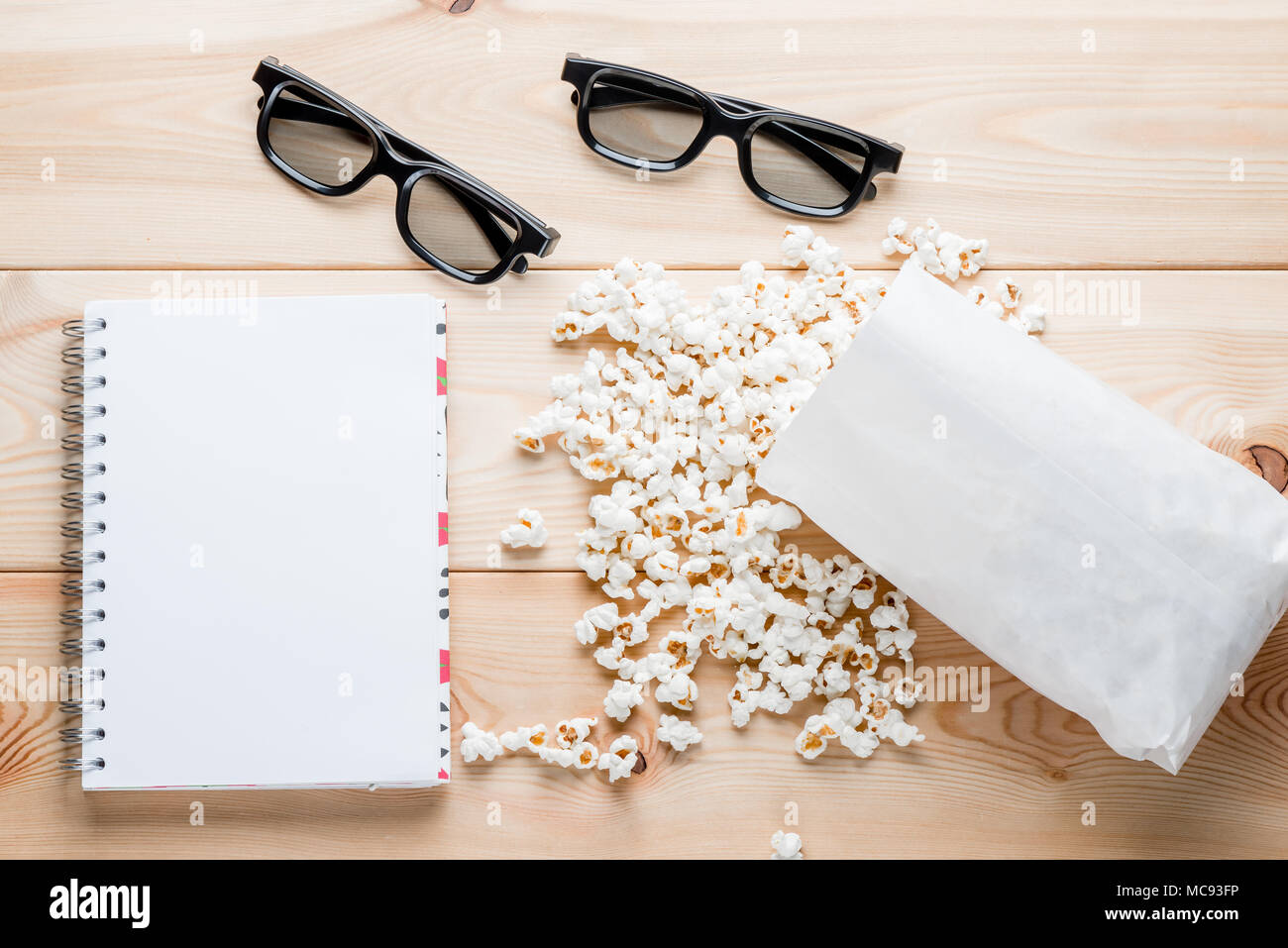 a notepad for entries, a pair of 3d glasses and salty popcorn on wooden ...