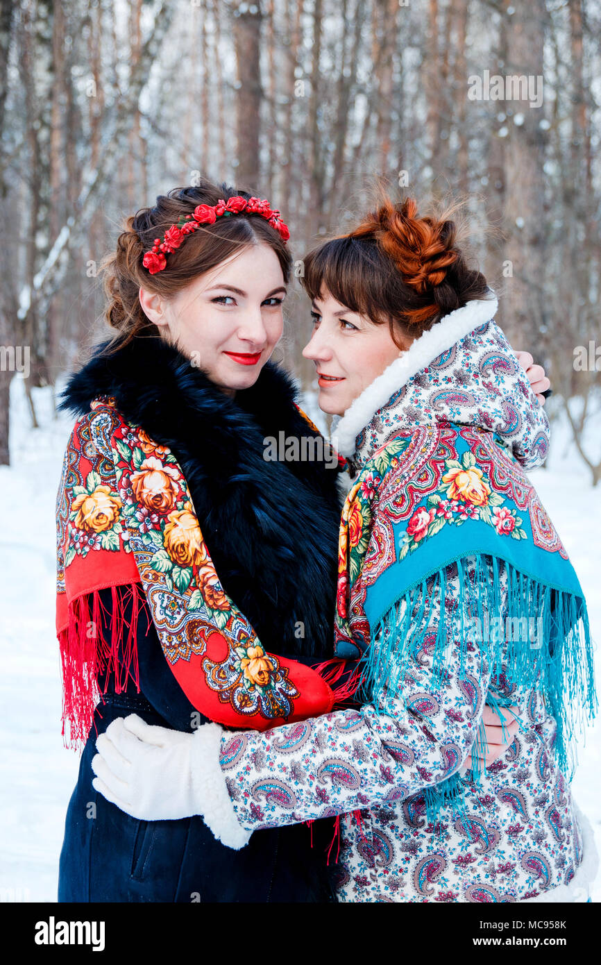 portrait of two girls in Slavic style in winter forest standing ...