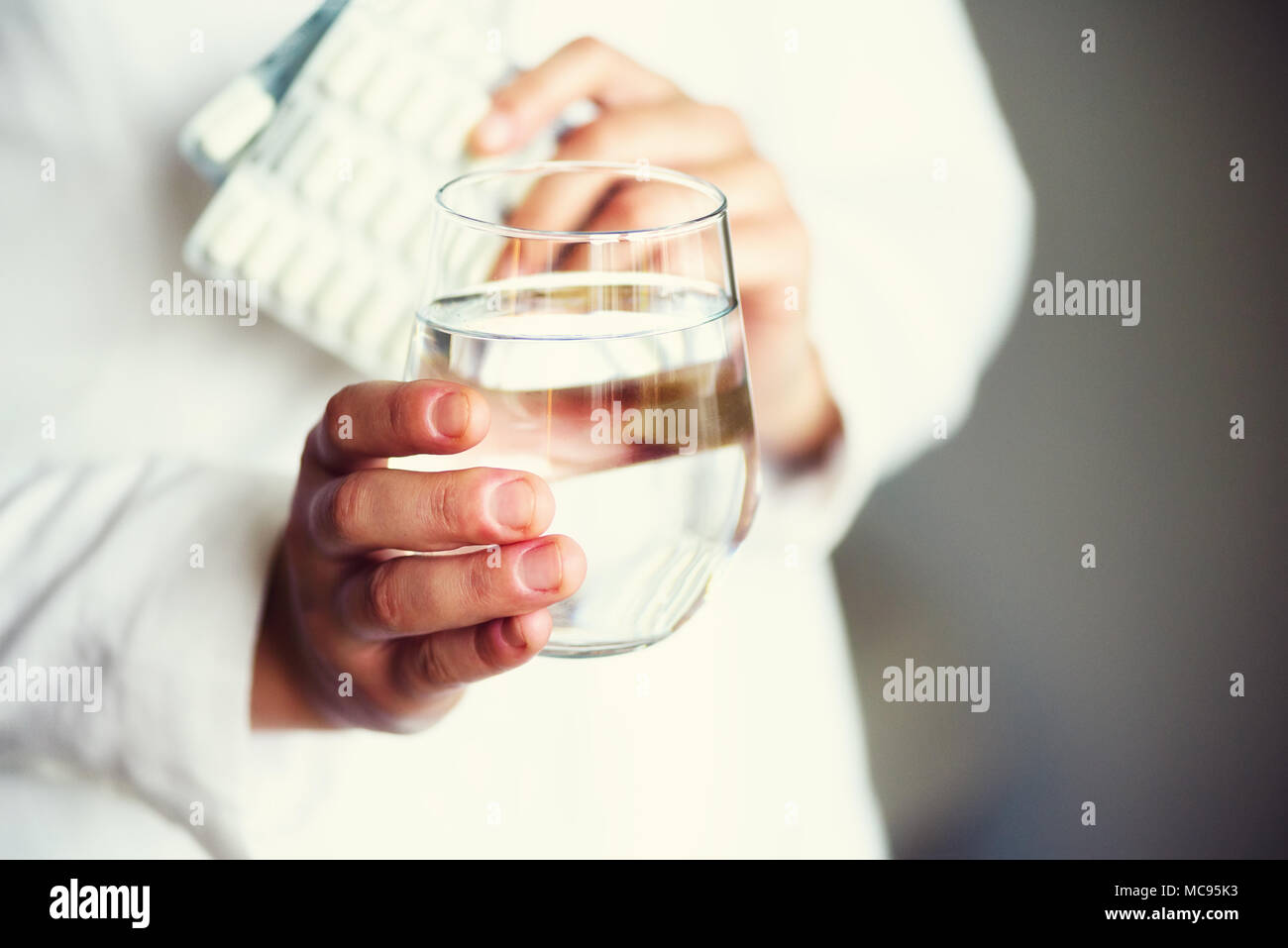 Doctor holding a glass of water with drug, pills, white background ...