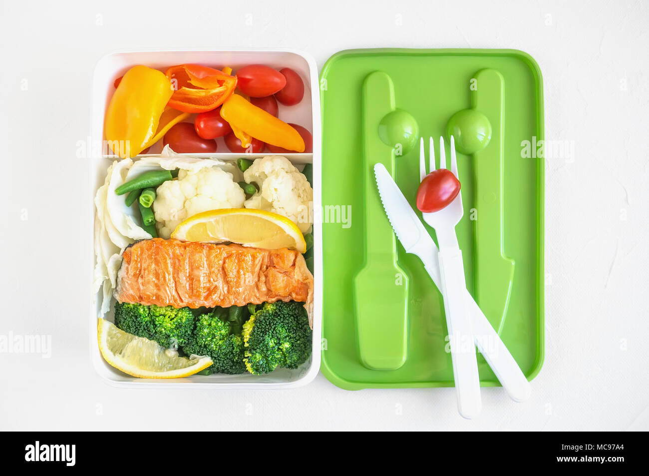 Green school lunch box with a piece of salmon on a couple, broccoli ...