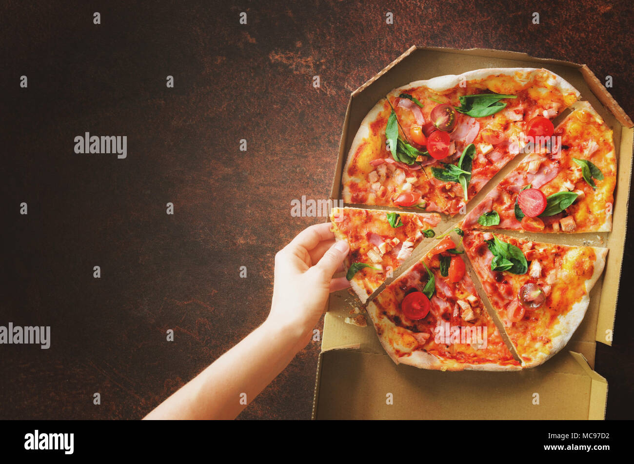 Female hand taking slice of fresh pizza from delivery box. Top view ...