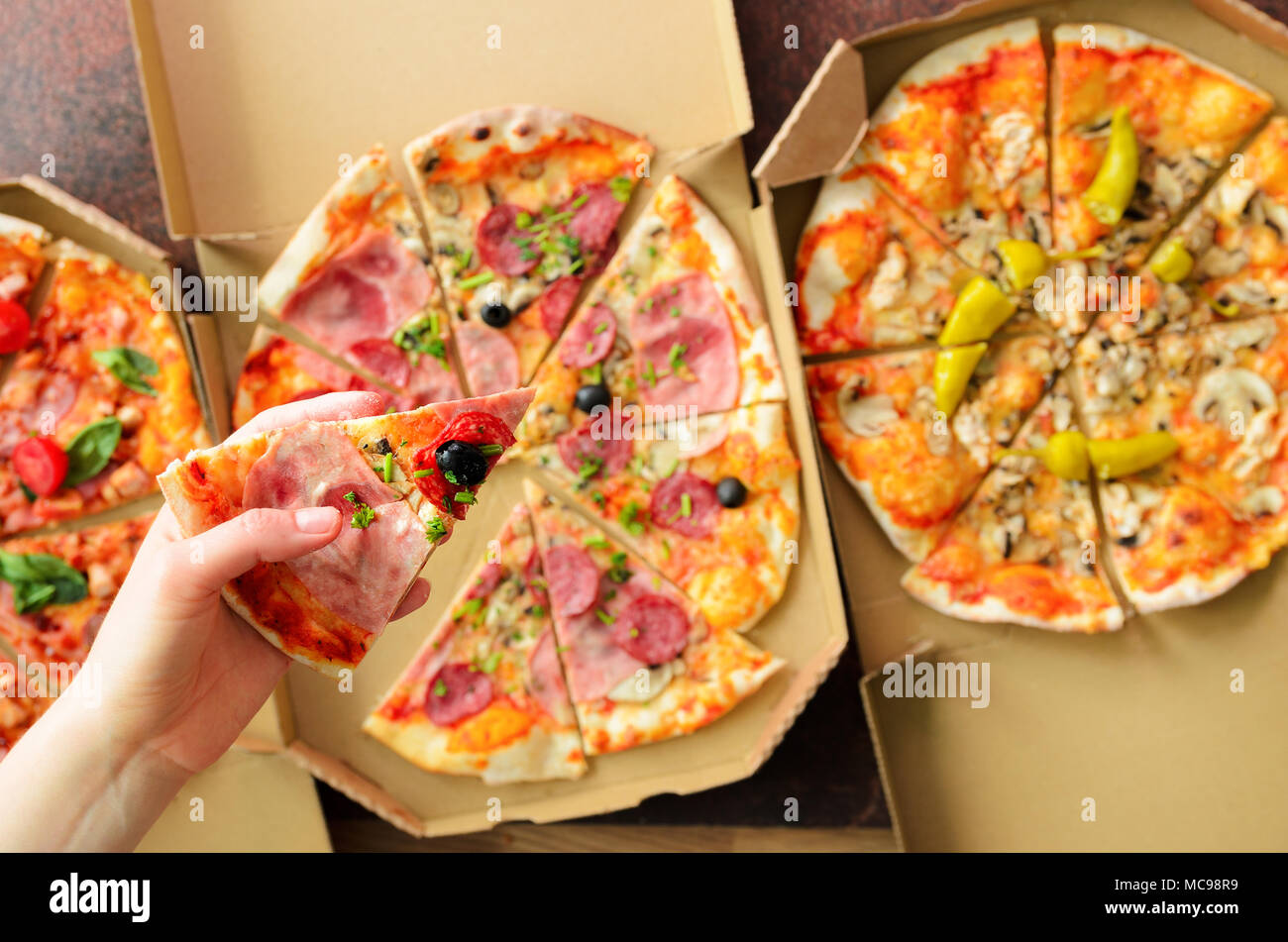Female hand taking slice of fresh pizza from delivery box. Top view ...