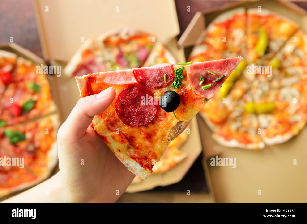 Female hand taking slice of fresh pizza from delivery box. Top view ...