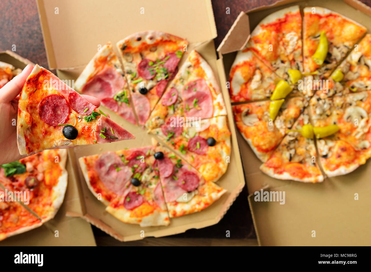 Female hand taking slice of fresh pizza from delivery box. Top view ...