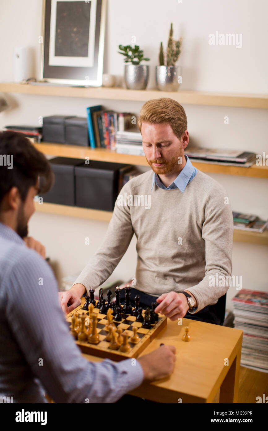 Two young men playing chess in room Stock Photo - Alamy