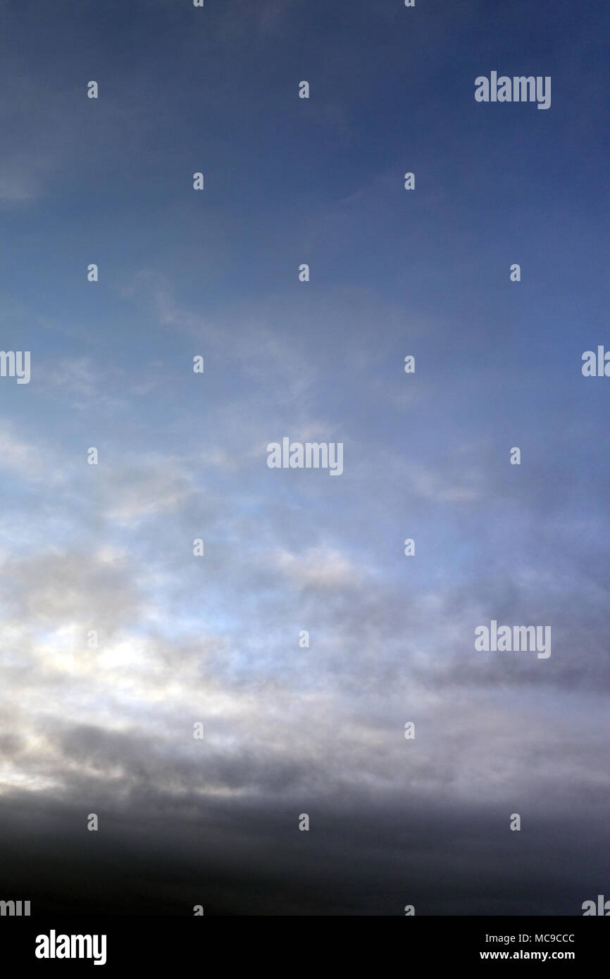 Wispy, translucent clouds against a darkening blue sky just before ...