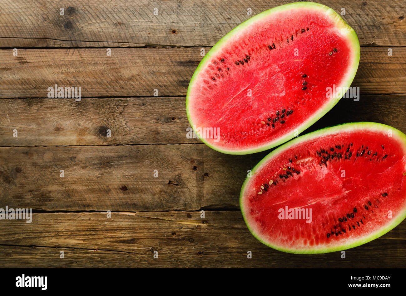 Tasty organic watermelon cut in half on wooden background with copy ...