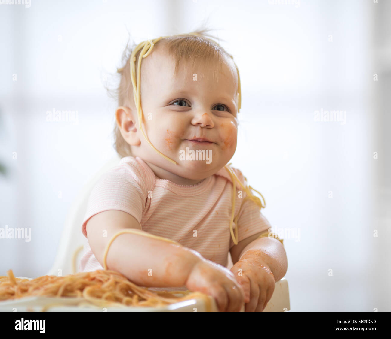 Happy little baby girl eating spaghetti Stock Photo - Alamy