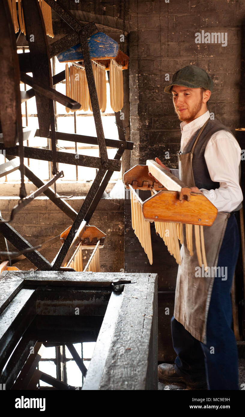 re-enactor demonstrates candle making in 1900's British working clothes ...