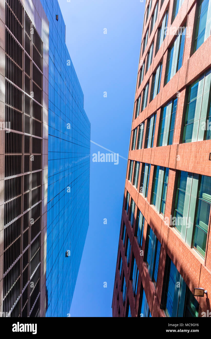 Track of plane in the sky between buildings Stock Photo - Alamy
