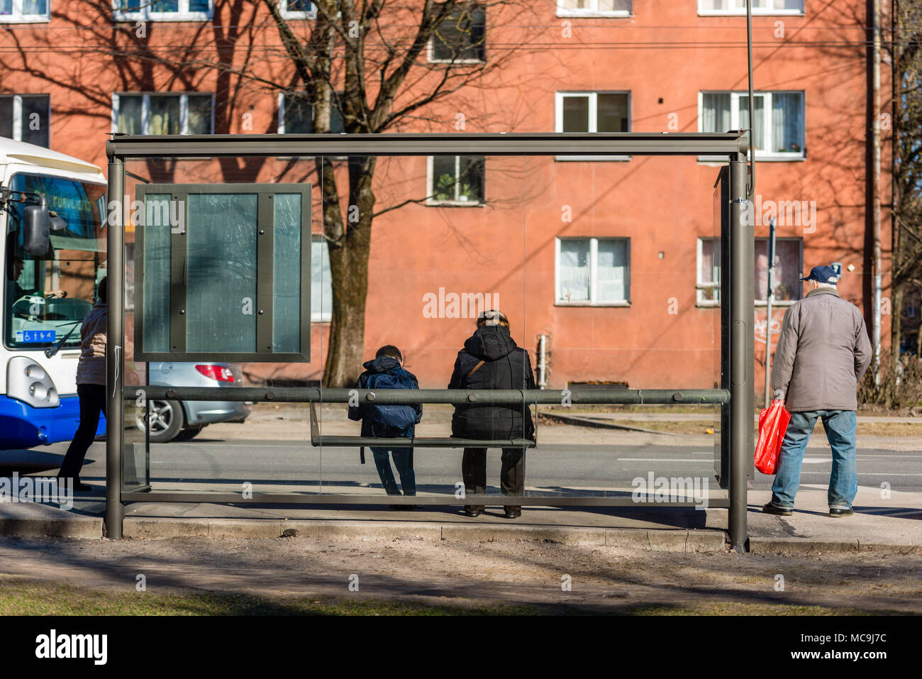 People waiting for the bus at the bus stop. View from the back Stock ...