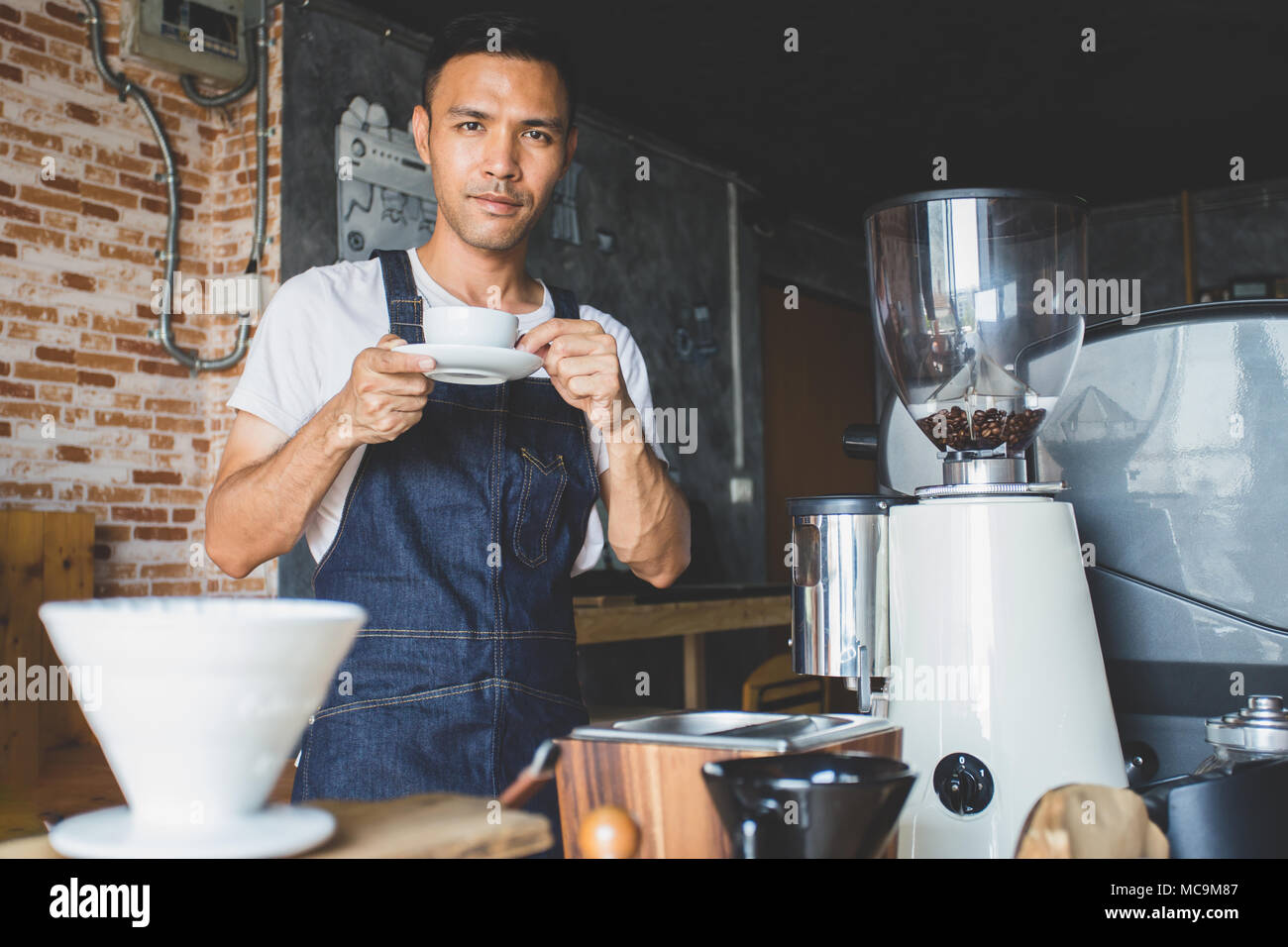 Portrait of handsome cheerful barista smiling and standing in coffee ...