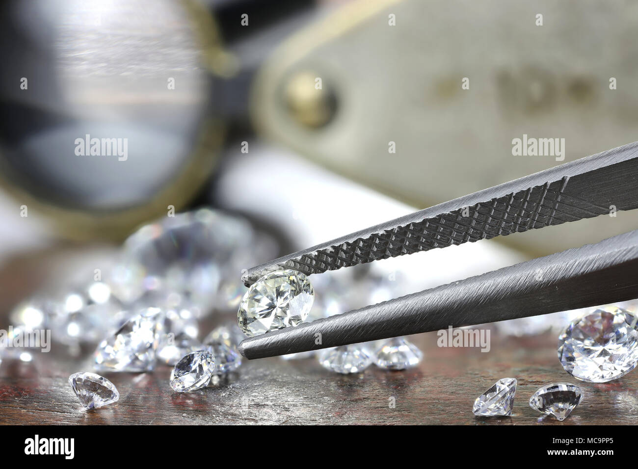 brilliant cut diamond held by tweezers Stock Photo - Alamy