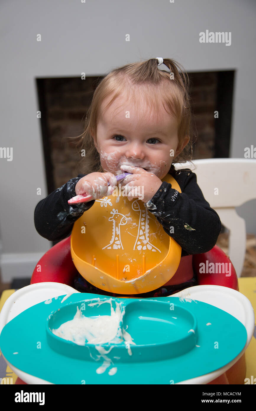 9 month old baby eating yoghurt - baby led weaning Stock Photo - Alamy