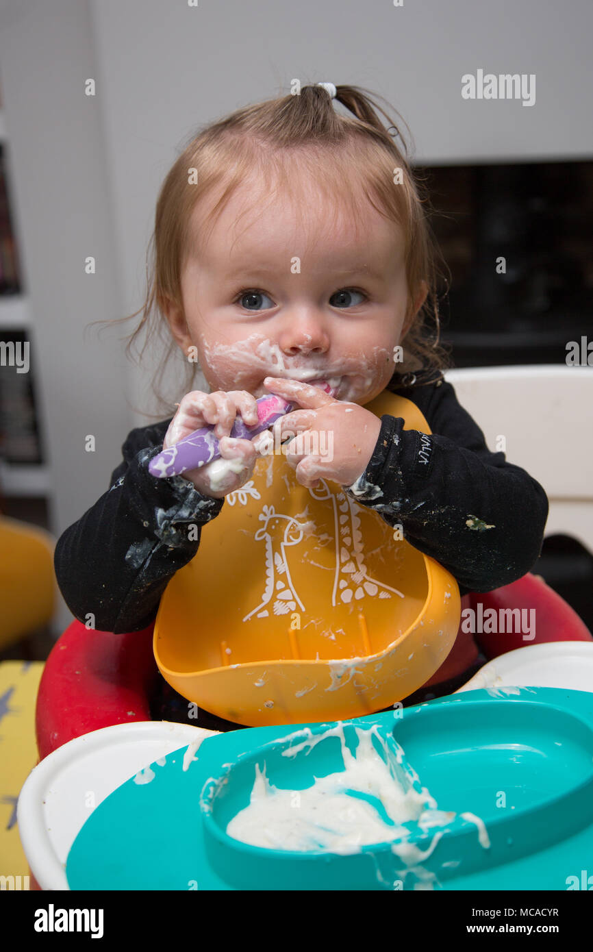 9 month old baby eating yoghurt - baby led weaning Stock Photo - Alamy